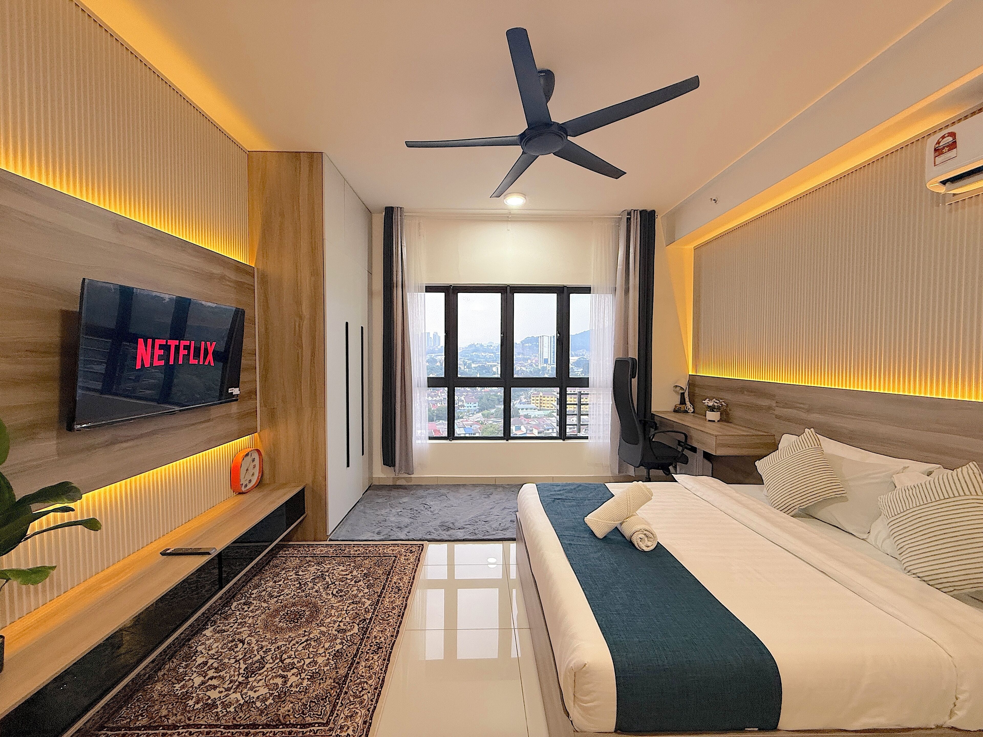 Quarto de hotel com cama, escrivaninha, televisão e vista para a cidade.