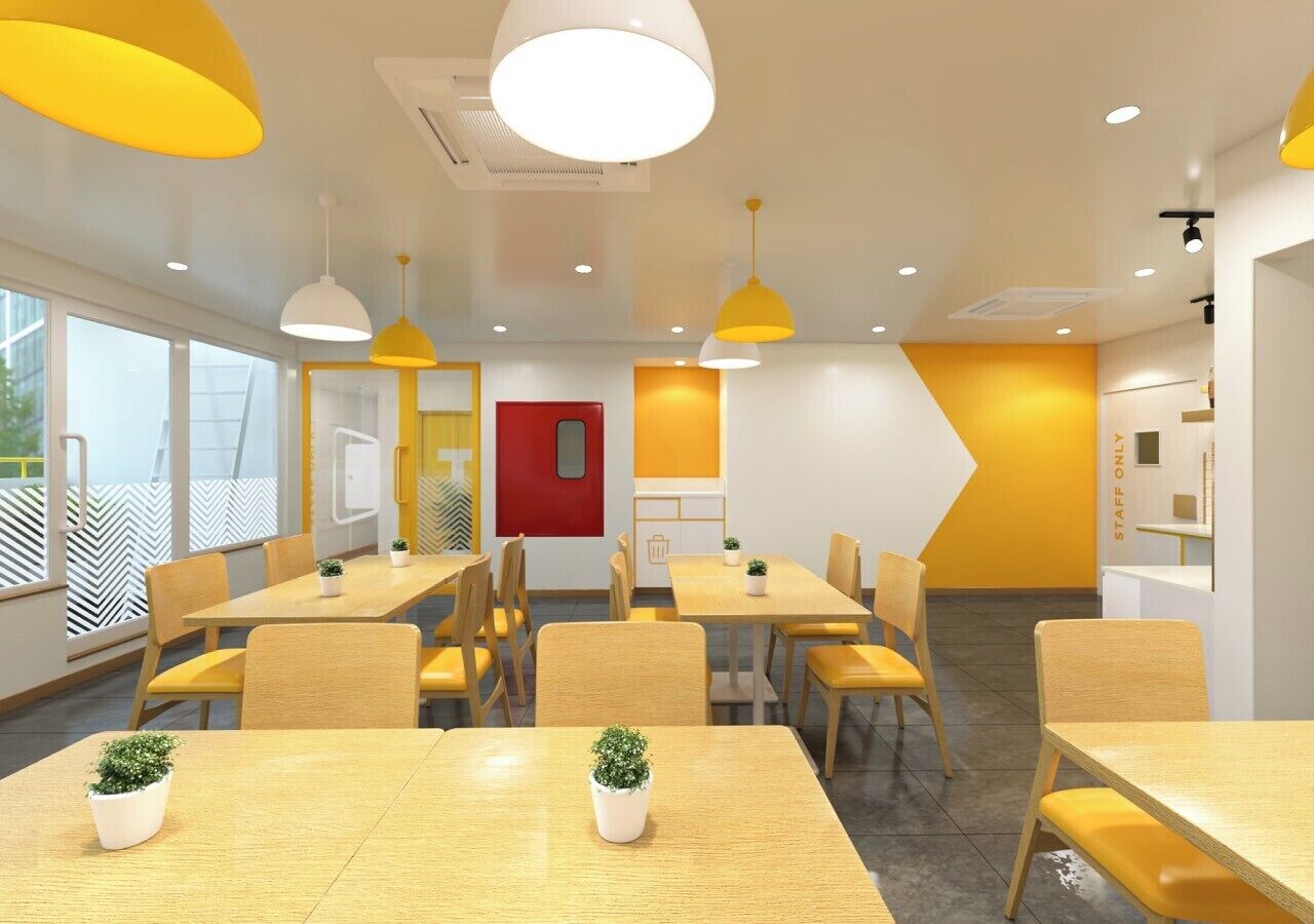 Uma área de jantar moderna com várias mesas e cadeiras, uma parede de destaque vermelha e iluminação pendente.