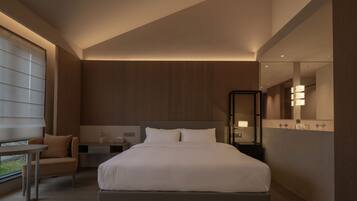 Quarto moderno com cama grande, mesas de cabeceira, uma cadeira e um espelho.