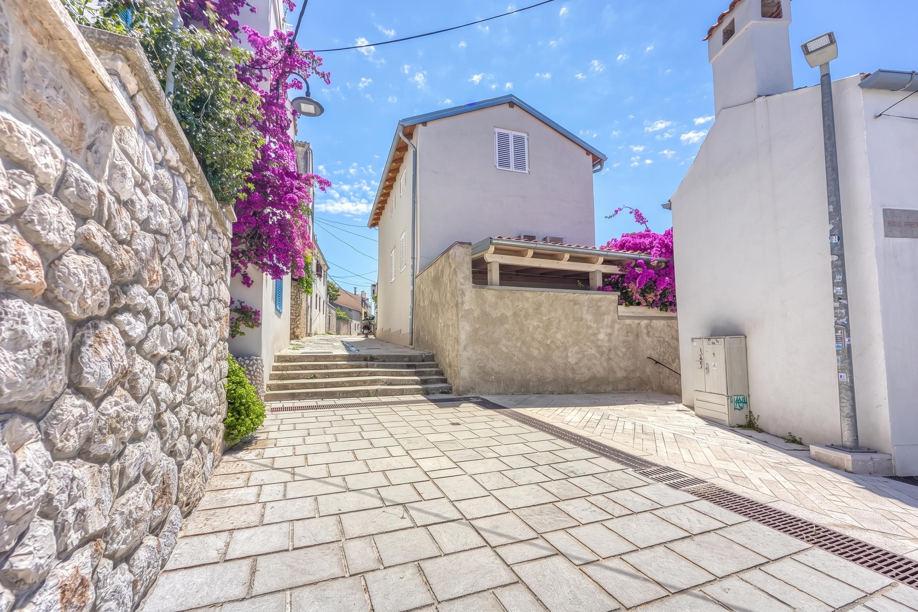 Uma rua estreita com paredes de pedra e um edifício com telhado inclinado.