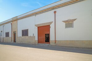 Um edifício com uma única porta vermelha, uma pequena janela e um cano visível.