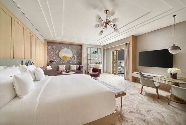 Quarto de hotel com uma cama grande, um sofá, uma mesa e uma televisão.