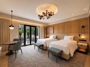 Quarto de hotel com duas camas, área de refeições e vista para o verde lá fora.