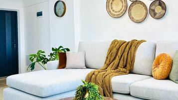 Uma sala de estar moderna com sofá, mesa de centro, pratos decorativos e luminária no teto.