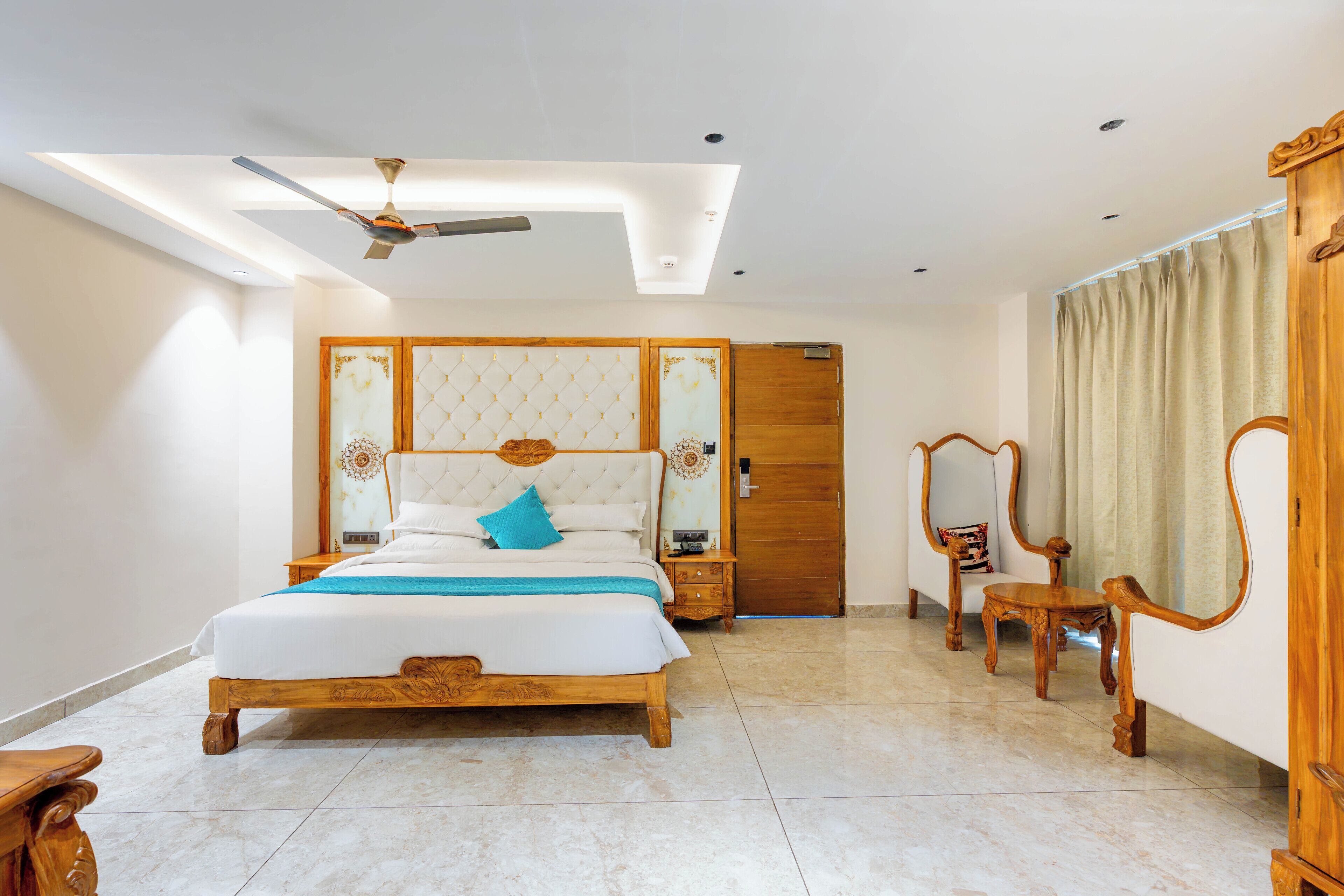 Quarto com cama, ventilador de teto, guarda-roupa de madeira e cadeira de madeira.
