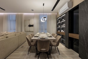 Uma zona de refeições moderna com uma mesa comprida posta para seis pessoas, rodeada por cadeiras bege.