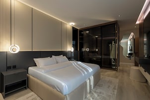 Quarto moderno com uma cama grande, mesas de cabeceira, um closet espaçoso e um banheiro com espelho.