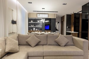 Uma sala moderna com um sofá, uma área de jantar com mesa posta e uma televisão.
