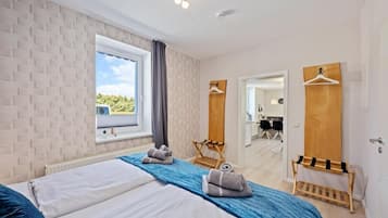 Quarto de hotel com duas camas, uma janela com vista, um varal de madeira e um espelho.