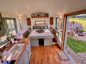 Quarto com cama, mesas de cabeceira, janela e vista para o exterior.