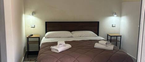 Quarto com uma cama grande, duas mesas de cabeceira e piso em azulejos.