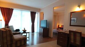 Quarto de hotel com sofá, televisão, secretária e cama.