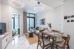 Uma sala de estar moderna com área de jantar, televisão e uma grande janela com cortinas.