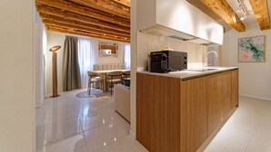Cozinha moderna com ilha de madeira, área de jantar com mesa e cadeiras, e teto com vigas aparentes.