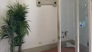 Quarto com lustre, planta em vaso, porta de vidro e placa na parede.