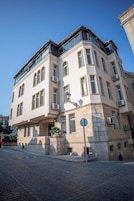 Um edifício de vários andares com estilo arquitetônico clássico, com janelas em arco e uma varanda.
