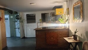 Quarto com balcão de madeira, uma cadeira, uma mesa e um espelho na parede.