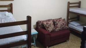 Quarto com beliches, um sofá e uma pequena mesa.