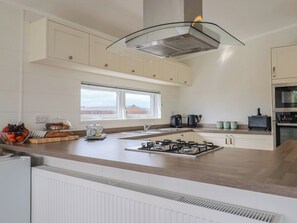 Uma cozinha moderna com fogão a gás, cafeteira e chaleira no balcão.