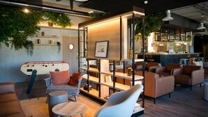 Uma área de estar moderna com sofás de couro, uma mesa de centro de madeira e um espaço de bar com prateleiras e plantas.