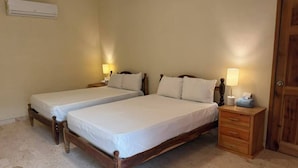 Quarto com duas camas de madeira, uma mesinha de cabeceira de madeira, um guarda-roupa de madeira e um aparelho de ar condicionado na parede.