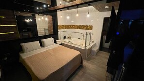 Um quarto moderno com uma cama grande, um chuveiro com divisória de vidro e uma TV de tela plana.