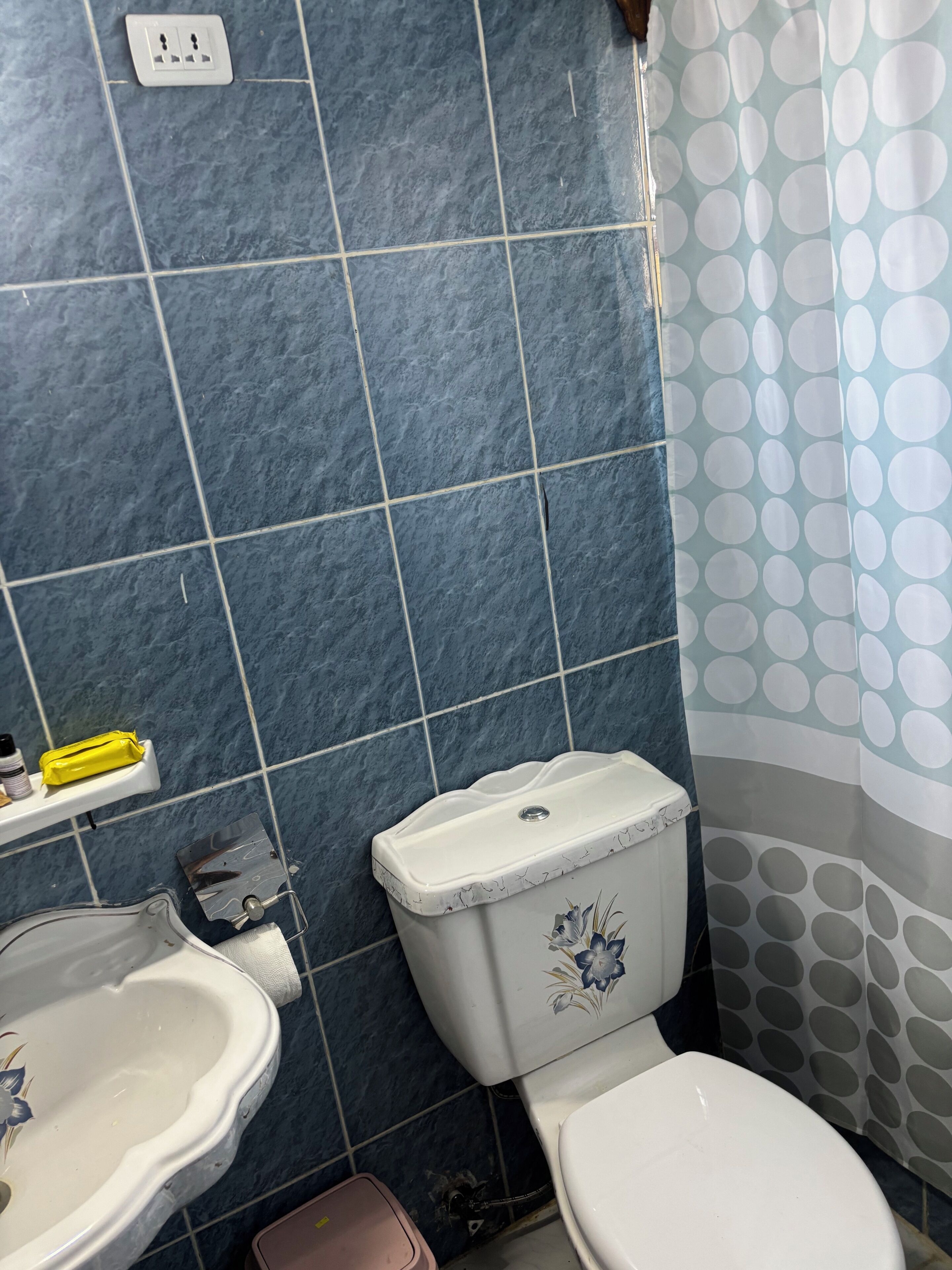 Casa de banho com sanita, lavatório e paredes revestidas a azulejos azuis.