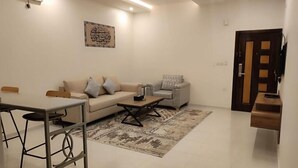 Uma sala de estar moderna com sofá, mesa de jantar, tapete estampado e porta com painel decorativo.