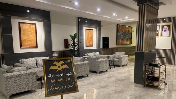 Um hall de hotel moderno com sofás estampados, uma mesa de recepção e quadros nas paredes.
