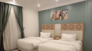 Quarto de hotel com duas camas, uma cabeceira decorativa e uma obra de arte floral na parede.