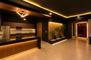 Cozinha moderna com bancada de mármore, armários de madeira e parede com detalhes em pedra.