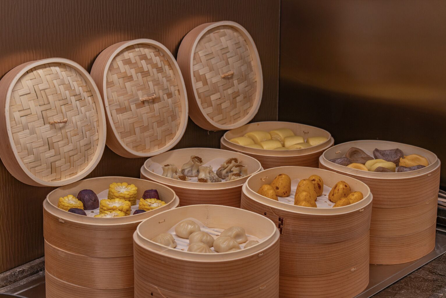 Diversos pratos de dim sum em cestos de bambu.