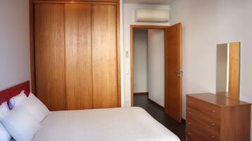 Quarto com cama, guarda-roupa de madeira e cômoda.