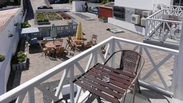 Terraço no telhado com área de estar externa, vista da rua e corrimão branco.