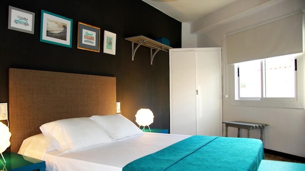 Quarto de hotel com cama, mesas de cabeceira, guarda-roupa e uma janela.