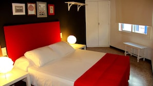 Quarto com uma cama grande, mesa de cabeceira com abajur, guarda-roupa e janela com vista.