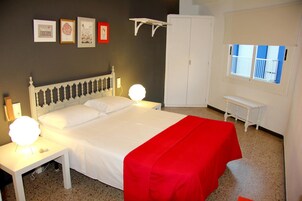 Um quarto com cama, mesas de cabeceira, guarda-roupa e janela.