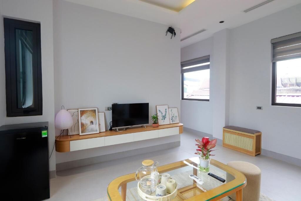 Uma sala de estar moderna com uma televisão de tela plana, uma mesa de centro com objetos decorativos, um sofá e um radiador.