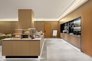 Uma área de café da manhã moderna com serviço de buffet, estação de café e vista para a cidade.