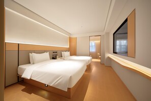 Quarto de hotel moderno com uma cama grande, mesas de cabeceira, uma escrivaninha e uma janela ampla.