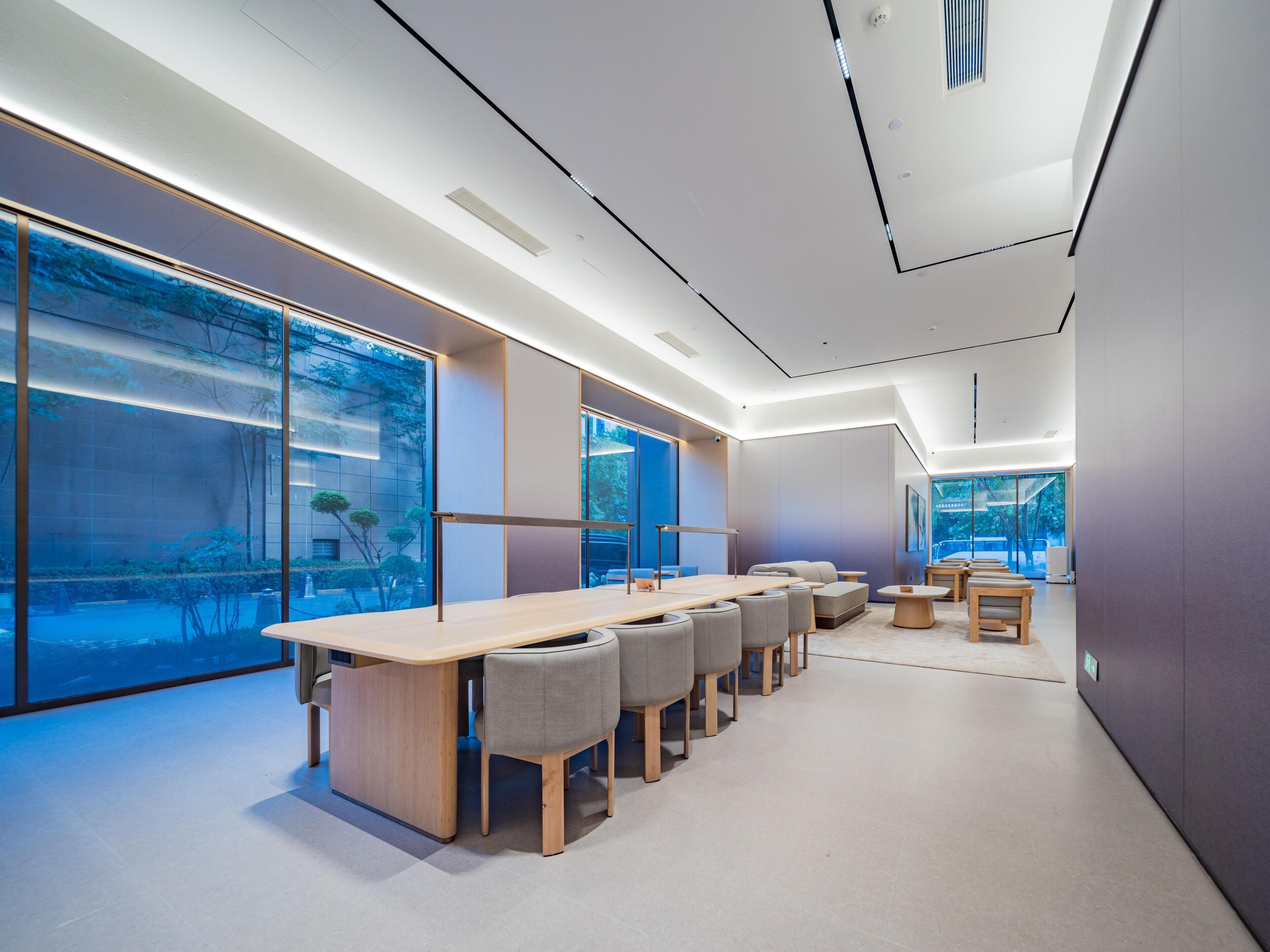 Uma sala de conferências moderna com uma mesa comprida, cadeiras e janelas amplas.
