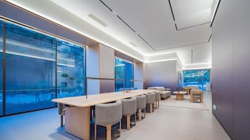 Uma sala de conferências moderna com uma mesa comprida, cadeiras e janelas amplas.