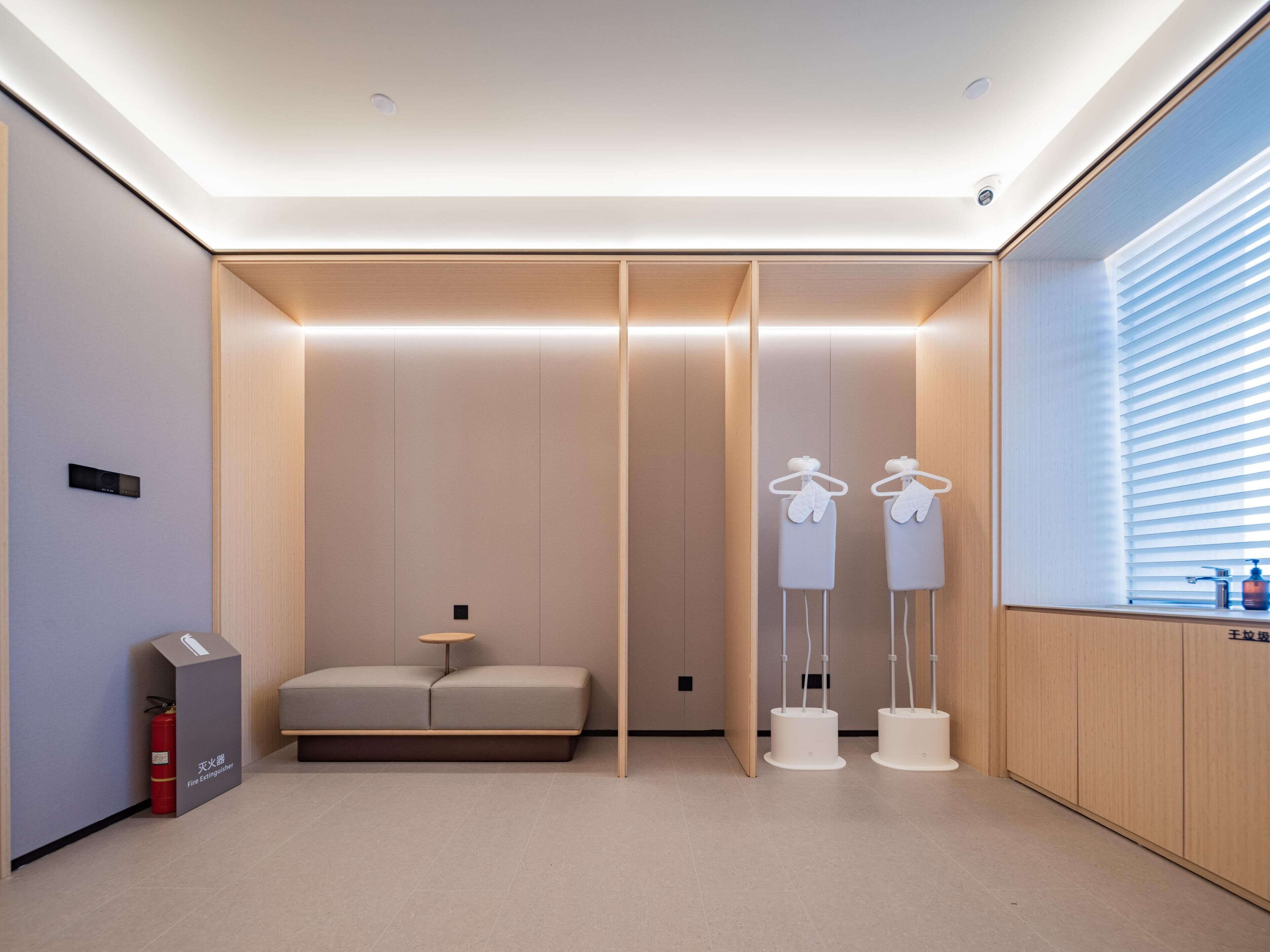 Quarto moderno e bem iluminado, com um sofá, uma mesinha e um extintor de incêndio.