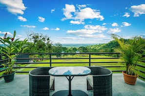 Uma varanda com móveis de vime e vista para uma paisagem verde.