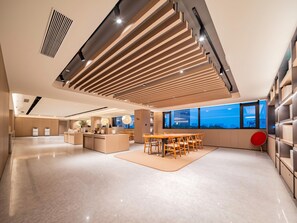 Um interior espaçoso e moderno, com área de jantar central, grandes janelas e um design de teto único.
