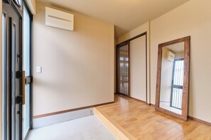 Um corredor com porta deslizante, piso de madeira e espelho na parede.