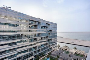 Um hotel moderno de vários andares, com varandas, área de piscina e vista para o mar.