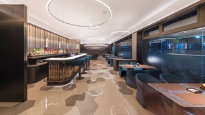 Uma área de bar moderna com balcão curvo, assentos com cadeiras azuis e piso estampado.