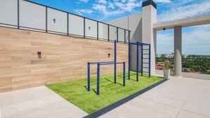 Uma área de ginástica ao ar livre com equipamentos de exercício em um terraço.
