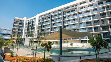Um hotel moderno com vários andares, um pátio central com piscina e áreas verdes ao redor.